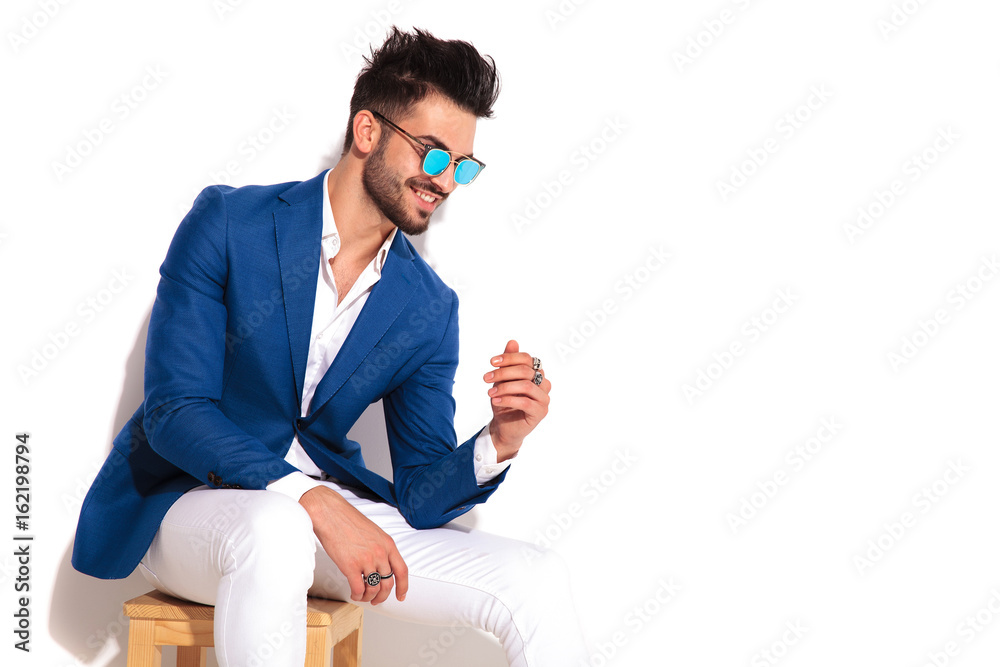 side view of laughing elegant young man sitting on chair Stock Photo ...