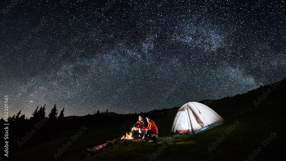Night camping in the mountains. Couple tourists have a rest at a ...