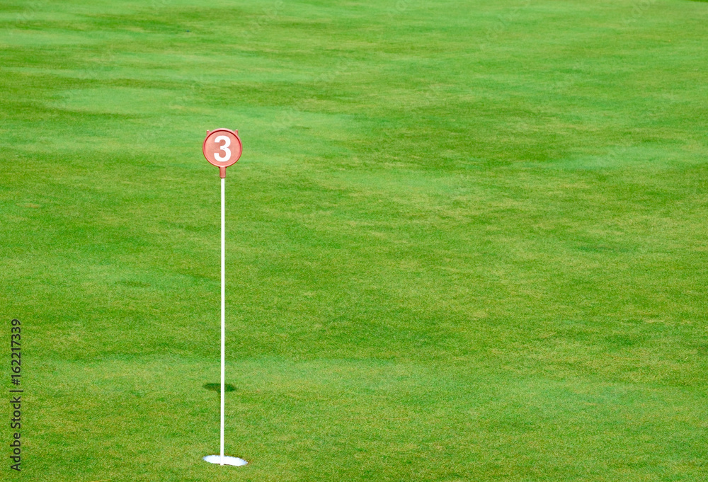 Golf practice putting green hole and marked with a red sign with space ...
