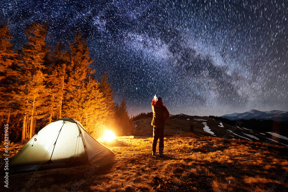 Male tourist have a rest in his camp near the forest at night. Man ...