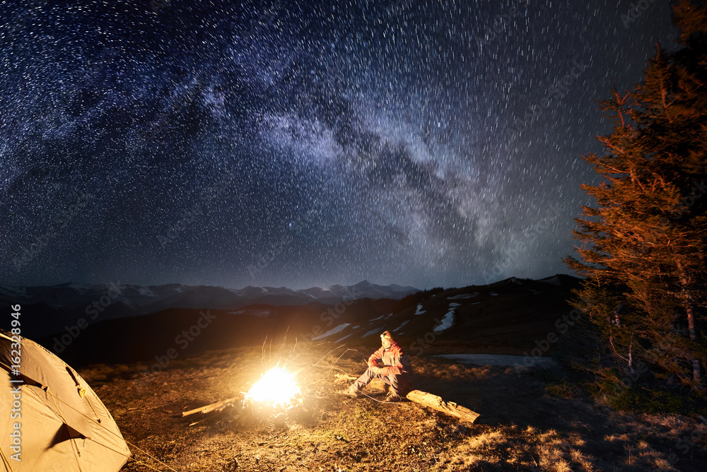 Male tourist have a rest in his camping at night. Man sitting near ...