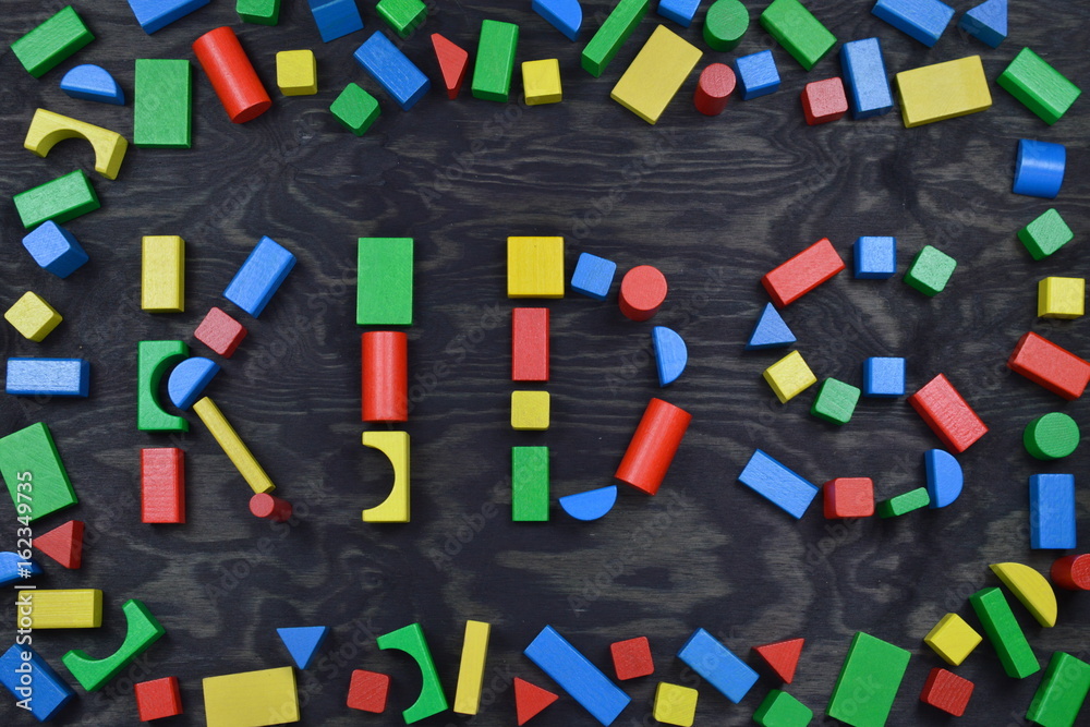 the word KIDS out of colorful wooden toy blocks on black wooden ...