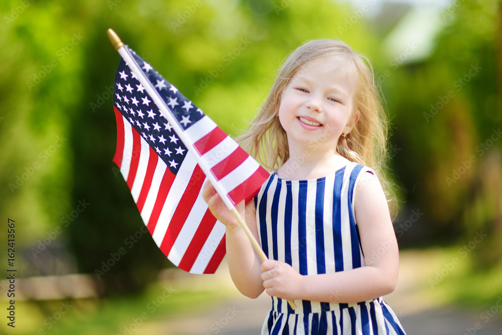 Adorable little girl holding american flag outdoors on beautiful summer ...