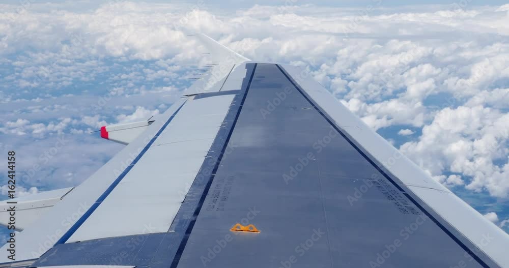 Aeroplane flying high up with views of the wing as it turns, banks, to ...