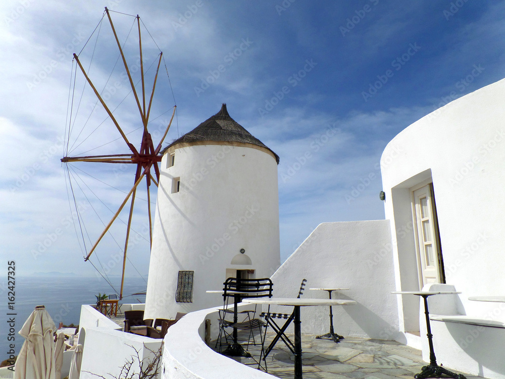 Cozy terrace in the afternoon sunlight at Greek style white windmill ...