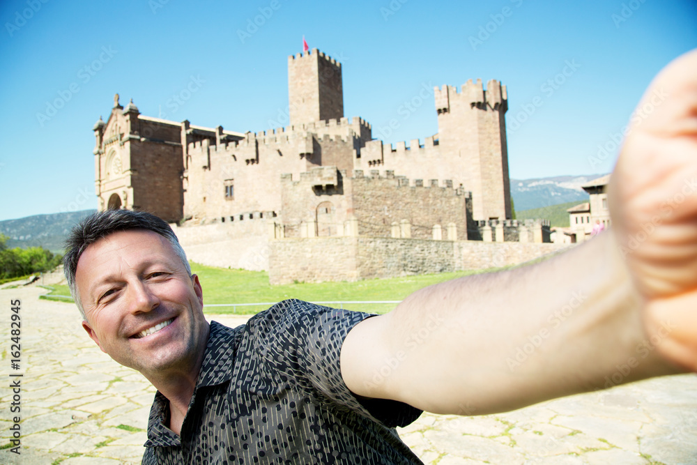 Foto de Happy smiling man making selfie over ancient spanish castle ...