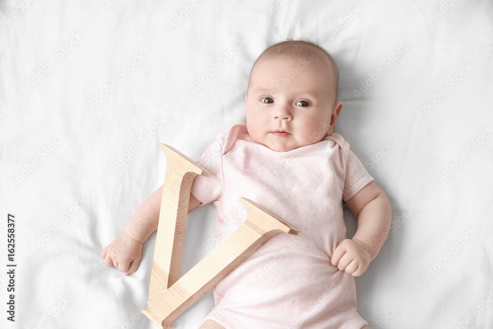 Cute baby with letter V lying on bed. Choosing name concept Stock Photo ...