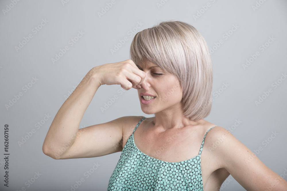 Female gesture smells bad. Portrait of woman wearing casually pinches ...