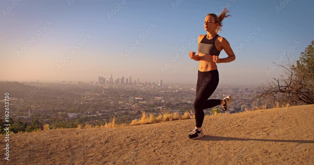 Fit woman Jogging through a park in the Hollywood Hills at sunrise ...