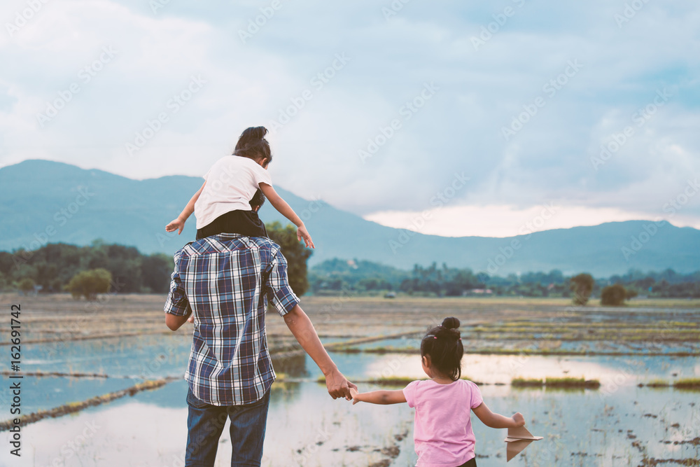 Back view of father and daughter playing together in the cornfield and ...