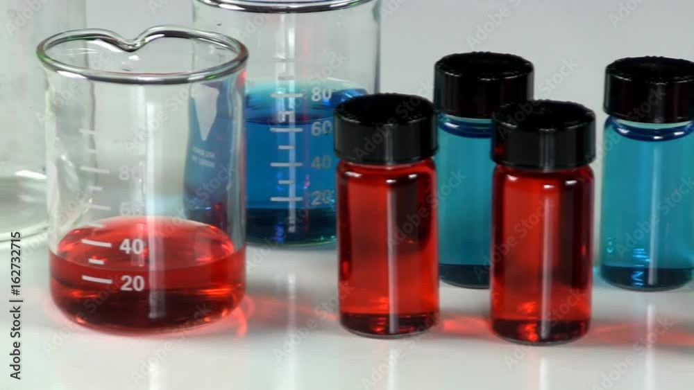 Vidéo Stock Pan from left to right of glass beakers and vials full of ...