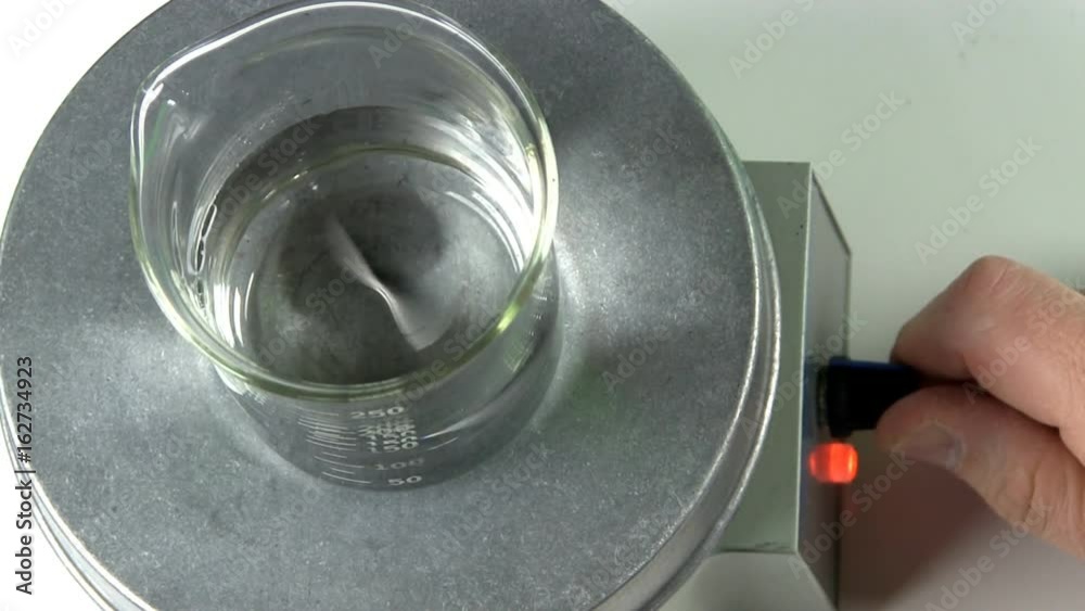 Top view of hand turning on magnetic stirrer which mixes liquid in ...