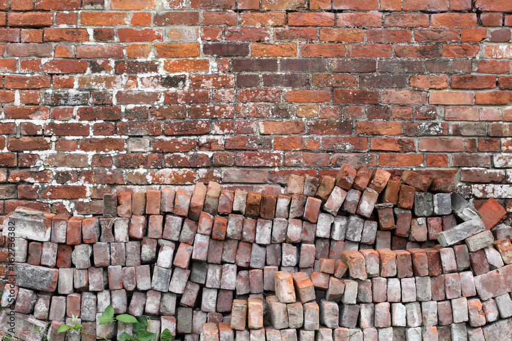 Old distressed red brick wall background with a pile of bricks in the ...