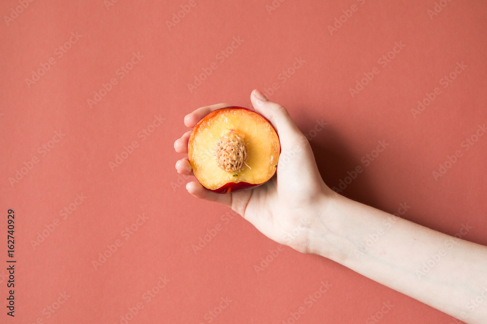 hand with a fresh juicy peach on a red background Stock Photo | Adobe Stock