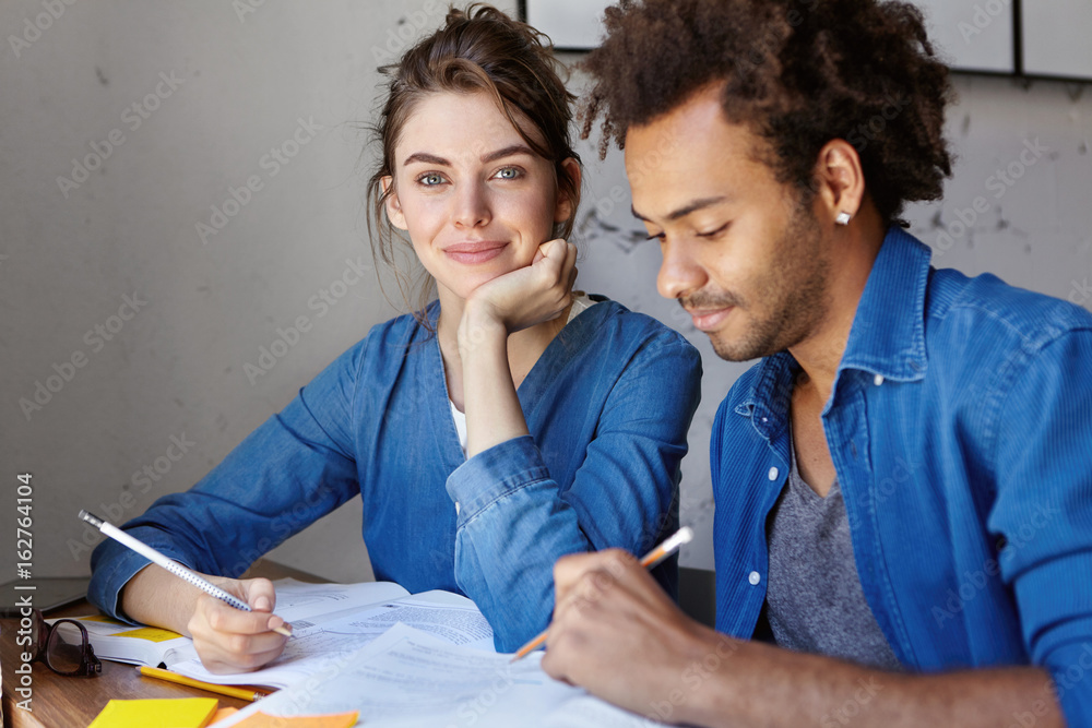 Beautiful young female tutor teaching Afro American student private ...