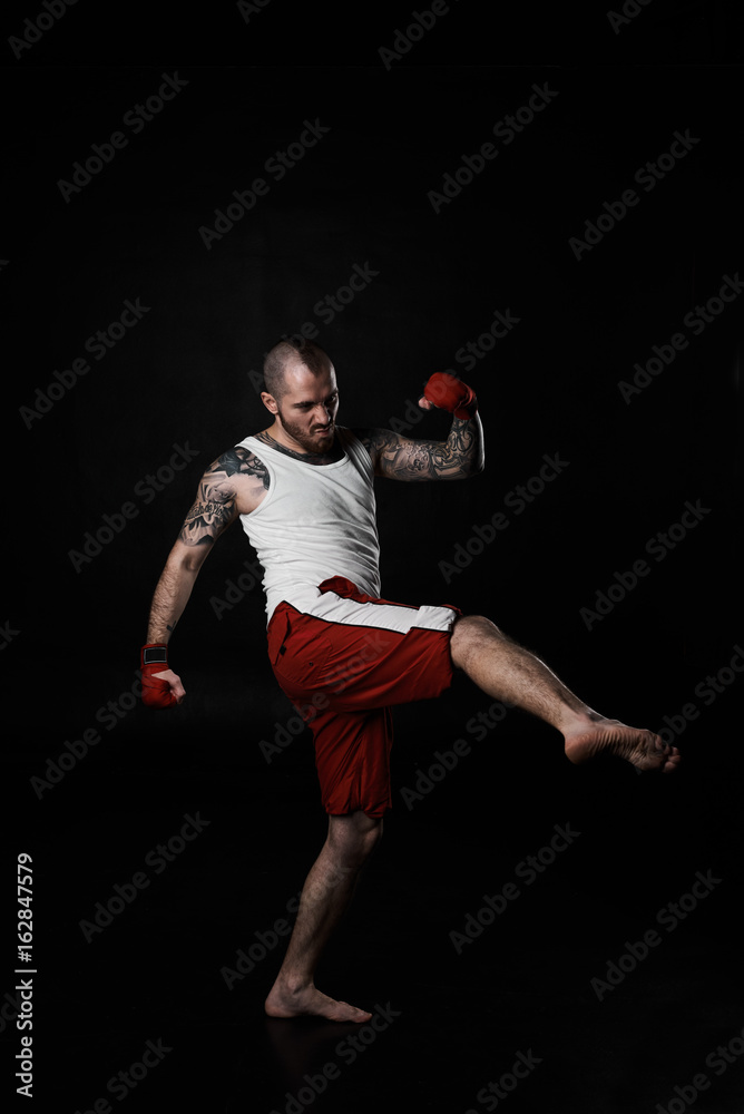 Confident muscular strong man wearing white A-shirt and boxing shorts ...