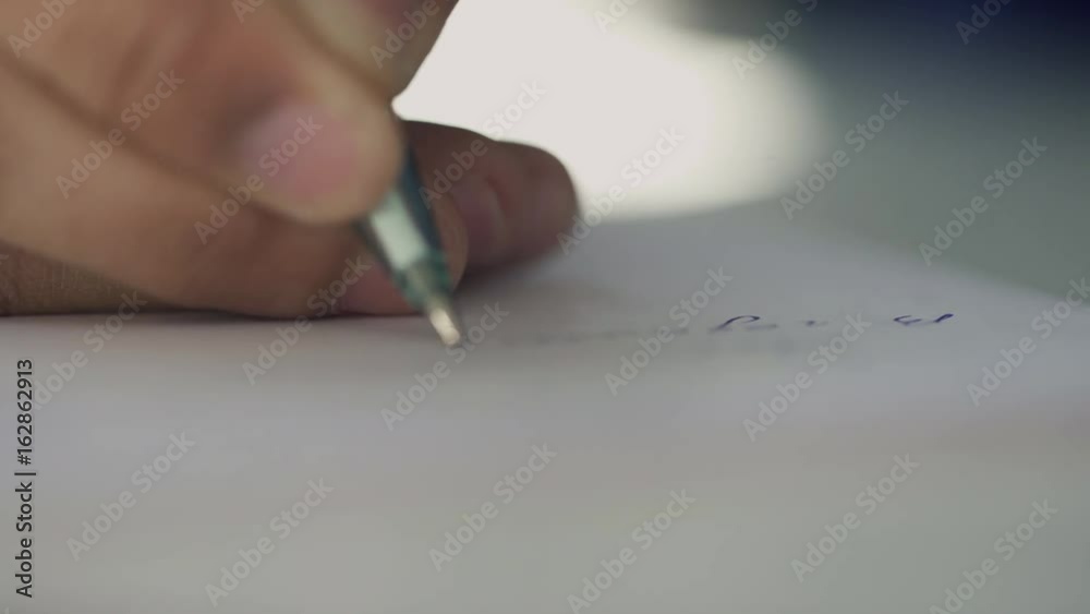 Close-up view on hand of man writing letter on paper indoors. Young ...