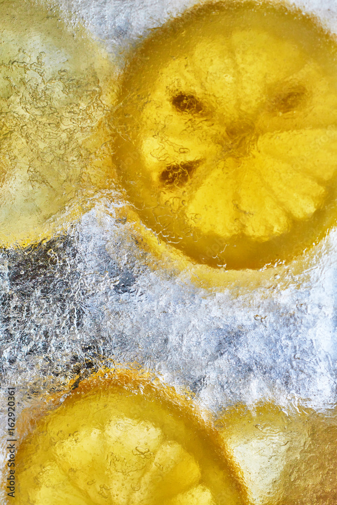 Lemon on the ice. Refreshing summer background of citrus. Yellow lemons ...