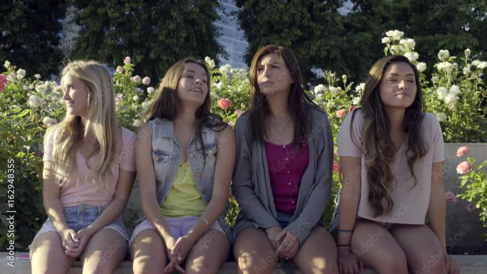 Teenage Girls Hang Out On A Wall, Beautiful Rose Garden Behind Them ...