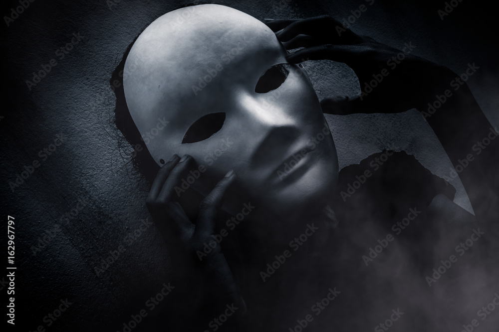 Mysterious woman in black wearing white mask hidden behind the dark ...