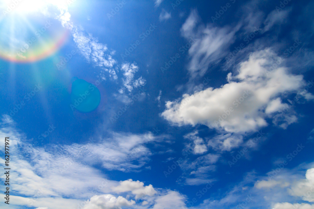 Flying softy clouds on blue sky and lens flare effect in windy time ...