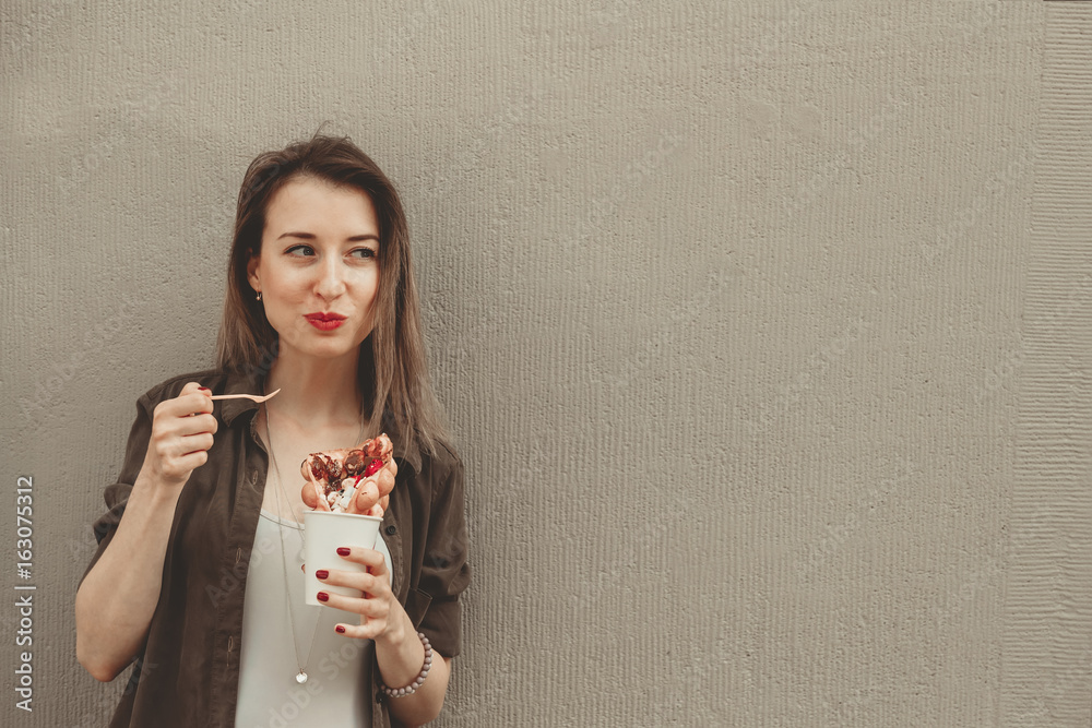 Poster Young woman eating bubble waffle with fruits, chocolate and ...