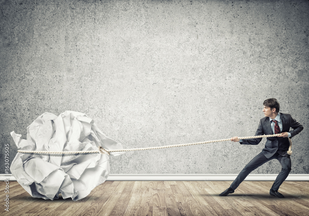 Man pulling with effort big crumpled ball of paper as creativity sign ...
