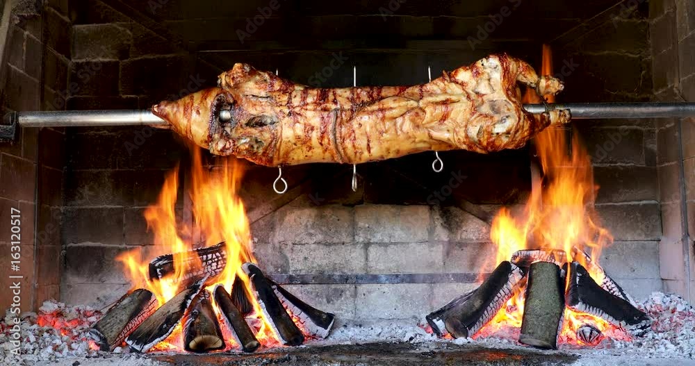 pig spinning on spit - cooking piglet in firewood grill Stock ビデオ ...