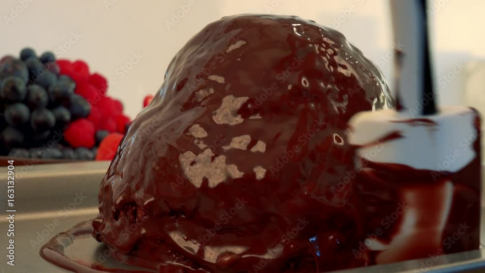 Chocolate coating is spread over a cake on a tray, a platter with mixed ...