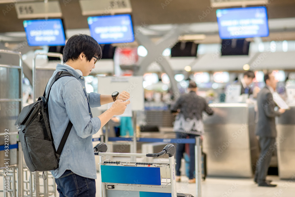 young asian man waiting for check in and dropping his luggage at ...