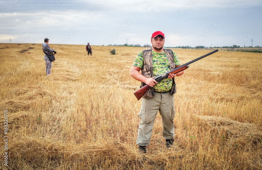Group of hunters with a guns moving through the field, looking for prey ...