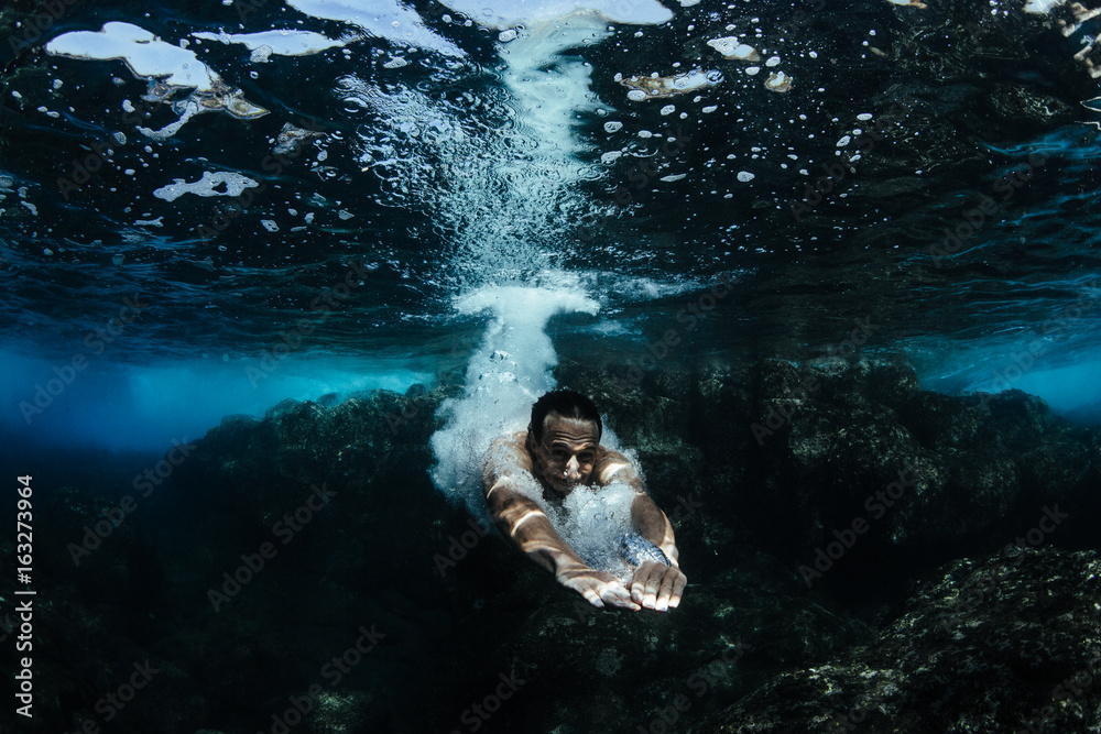 Underwater view of a Man diving into ocean over shallow reef, Kalapana ...
