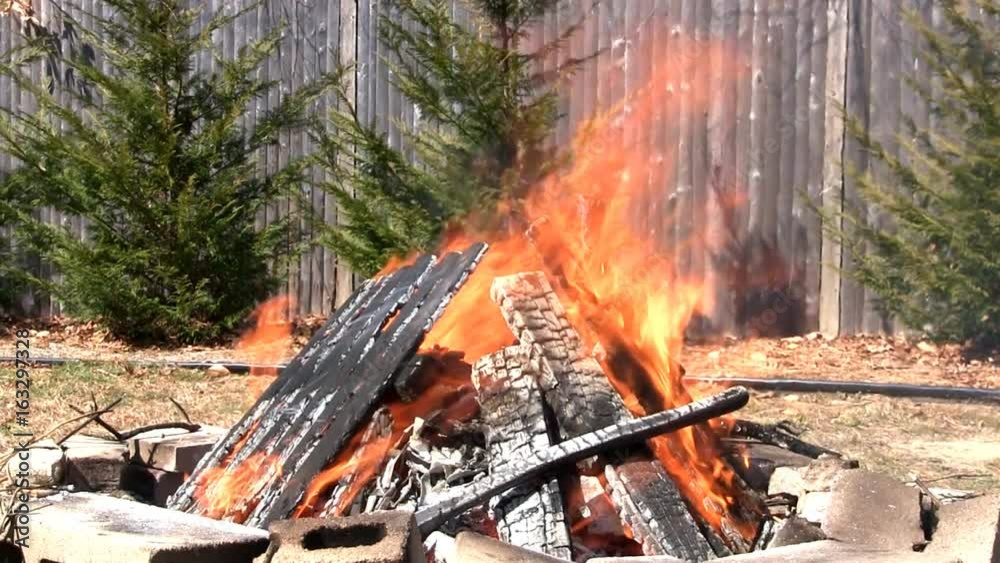 Burning excess lumber during cleanup in backyard fire pit. Wind fuels ...