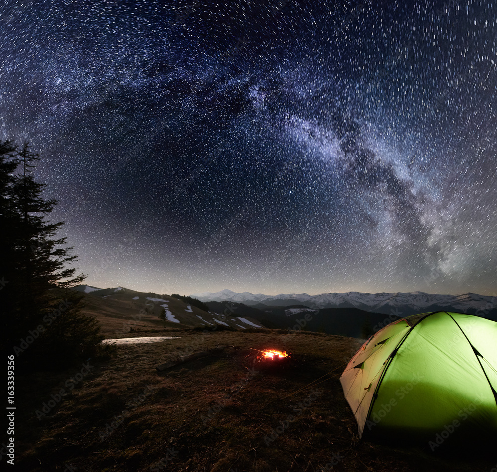 Night camping in the mountains. Illuminated tent and campfire under ...