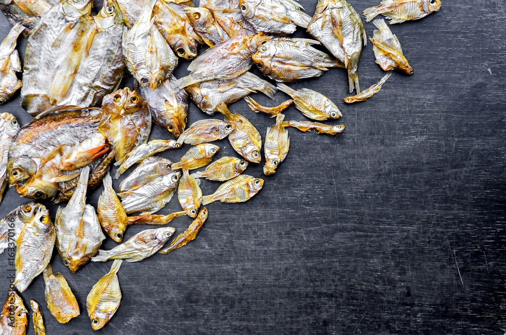 Dry fish with sunny on black wooden floor, small dried fish and pattern ...
