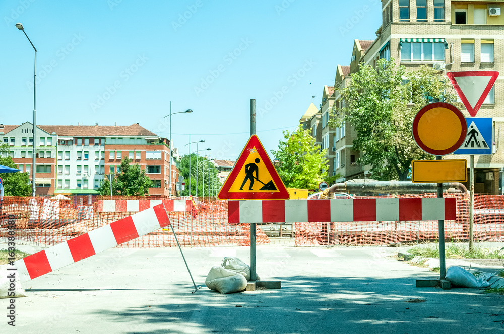 Work ahead construction site warning sign with barricades on the street ...