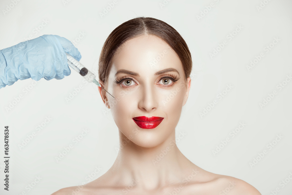 Smiling beautiful woman ready for anti aging serum shot in cheek ...