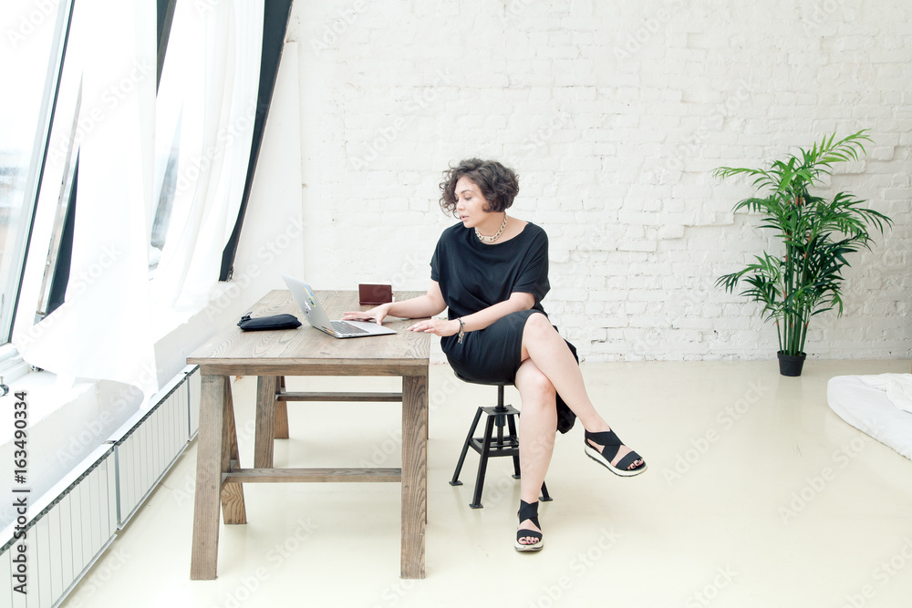 Young plus size female model sitting in front of the table and working ...