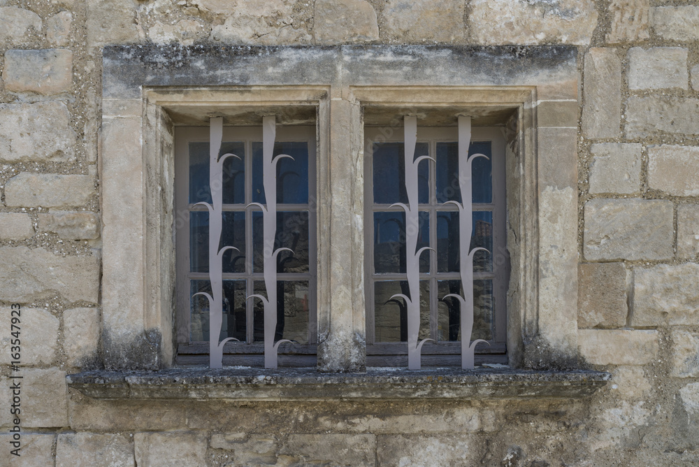 Old, worn window with ornamented iron bars in Les Baux, France Stock ...