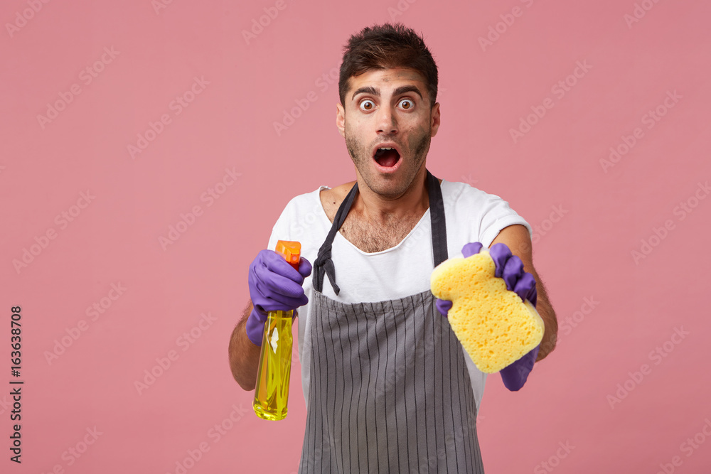 Untidy janitor wearing apron and rubber gloves looking with bugged eyes ...