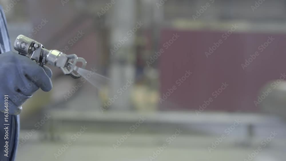 Arm hand holding industrial size spray gun used for industrial painting ...