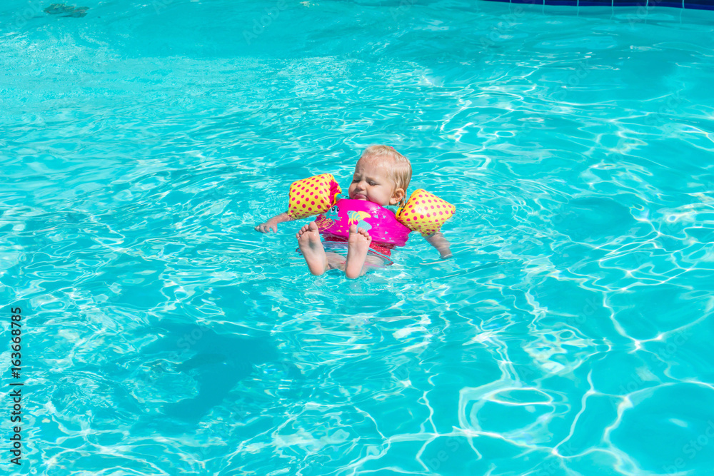 Little blonde girl floating in a swimming pool with her feet up Stock ...
