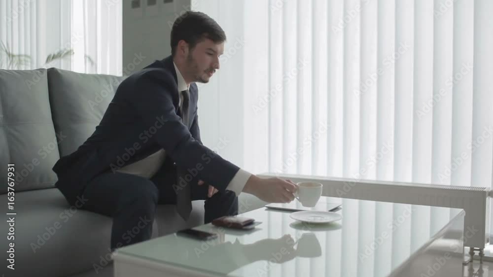 Disapointed businessman drinks a coffee and waits a boarding on the ...