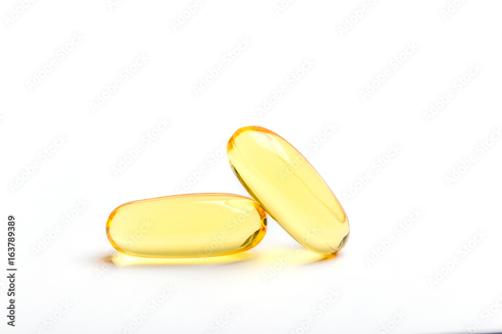 Two yellow soft gelatin capsules contain of fish oil supplement ...