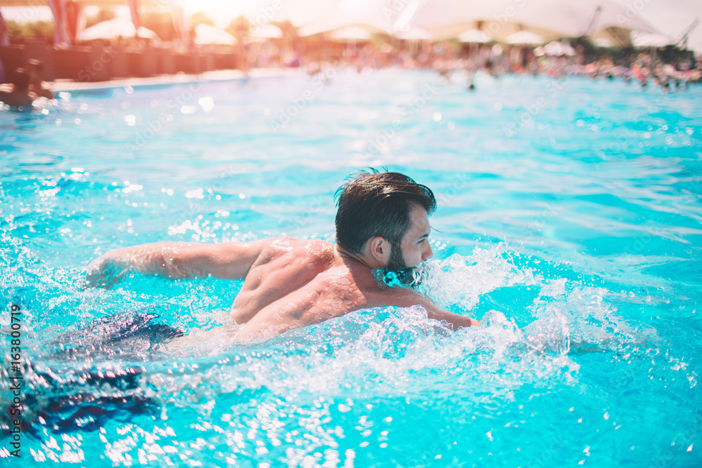 Summer photo of muscular smiling man in swimming pool. Happy male model ...