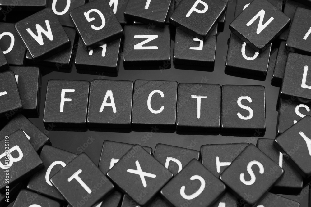 Black letter tiles spelling the word "facts" on a reflective background ...