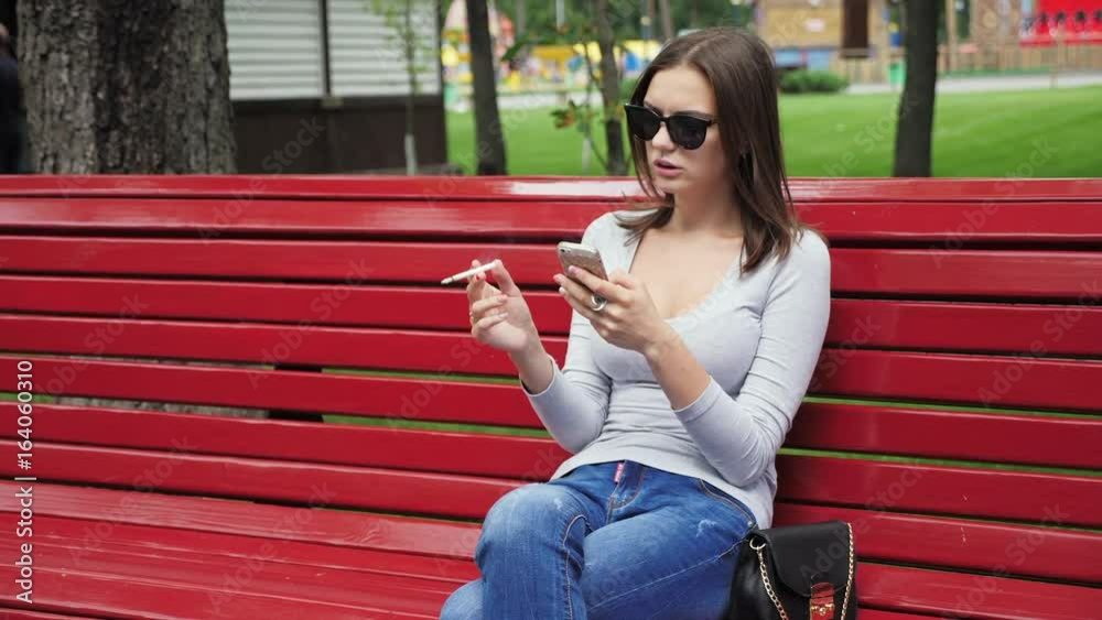 Young pretty girl smoking cigarette outdoors in a park bench Stock ...