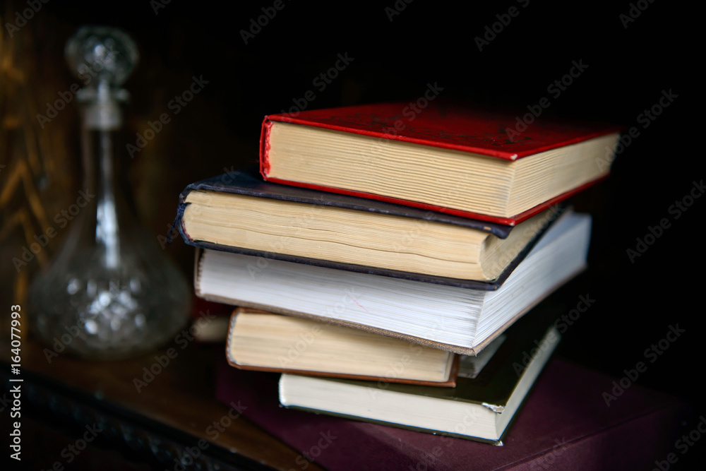 Paper books in a pile and a carafe of alcohol on the shelf intellectual ...