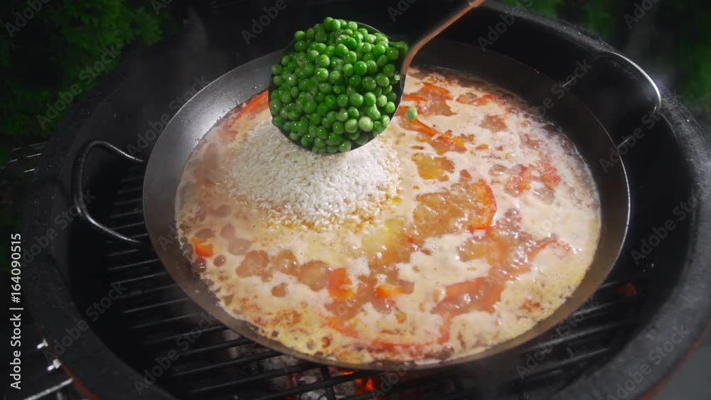 Video Stock The cook makes paella on the open fire and adds green pea ...