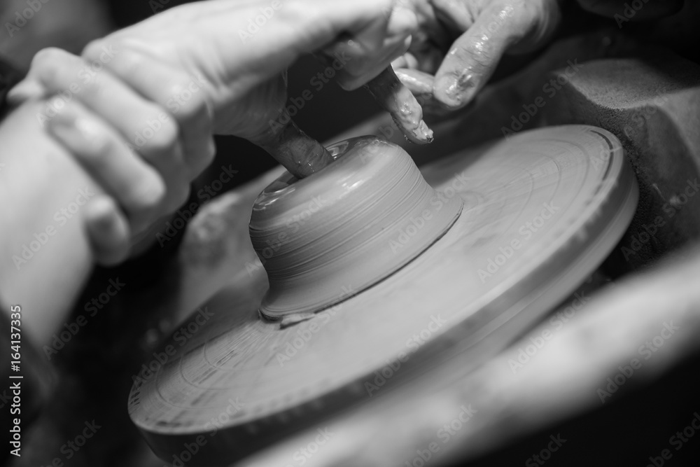 Hands working on a spinning pottery wheel, making pottery out of clay ...